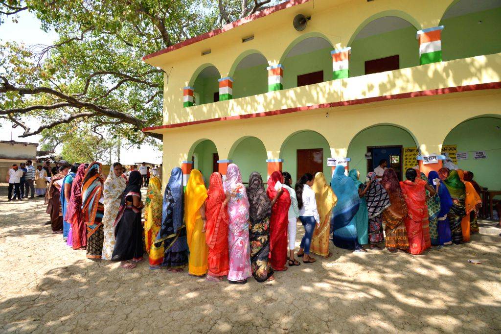 Voters wait in a queue at a polling station to cast their votes for the ...