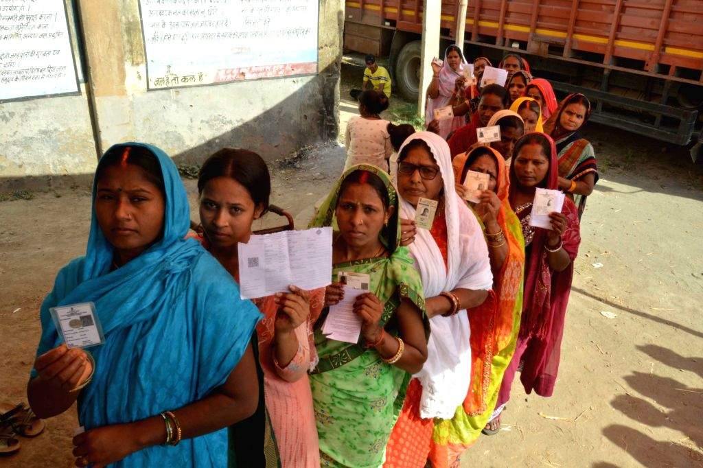 Voters wait in a queue at a polling station to cast their votes for the ...
