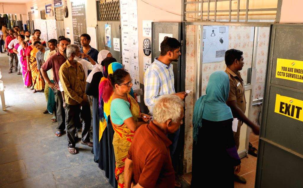 Voters wait in a queue at a polling station to cast their votes for the ...