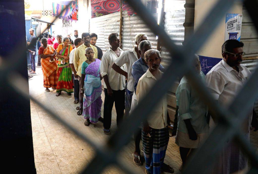 Voters wait in a queue at a polling station to cast their votes for the ...