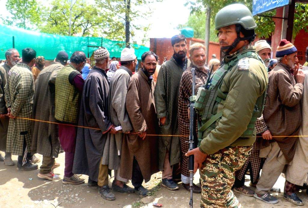 Voters wait in a queue at a polling station to cast their votes for the ...