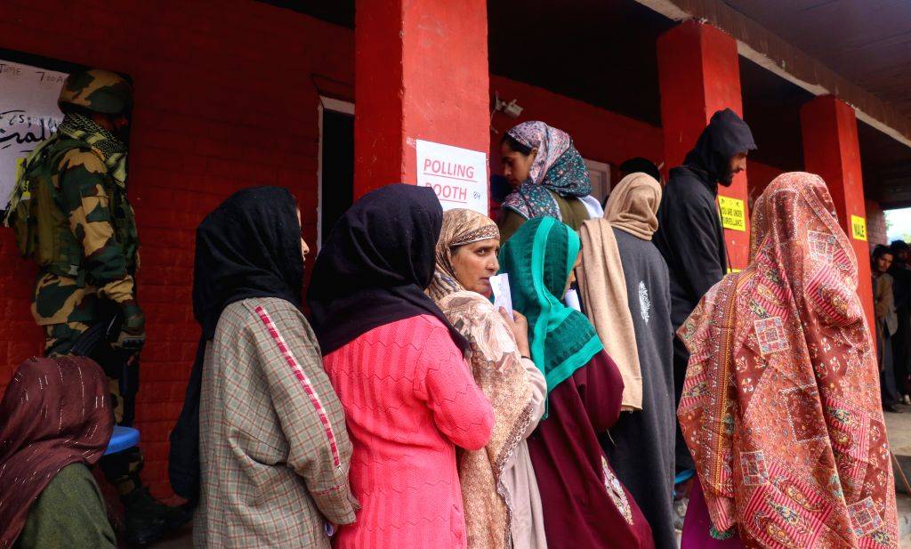 Voters wait in a queue at a polling station to cast their votes for the ...