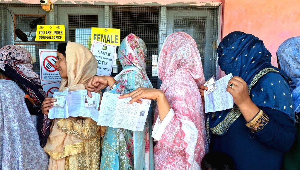 Voters wait in a queue at a polling station to cast their votes for the ...
