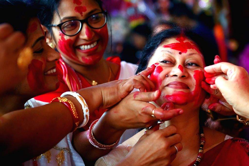 Women apply vermillion powder on each other as they participate in ...