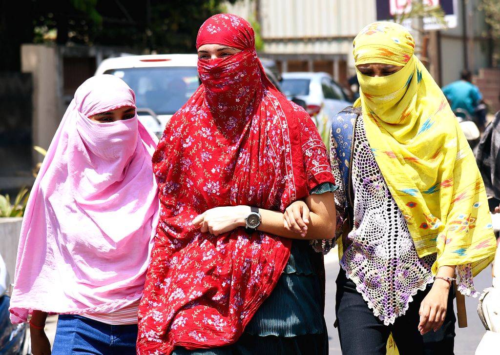 Women cover their faces with dupattas to shield from the scorching heat