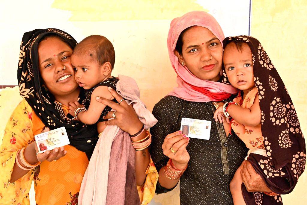 Women show their identity cards as they wait to cast their votes