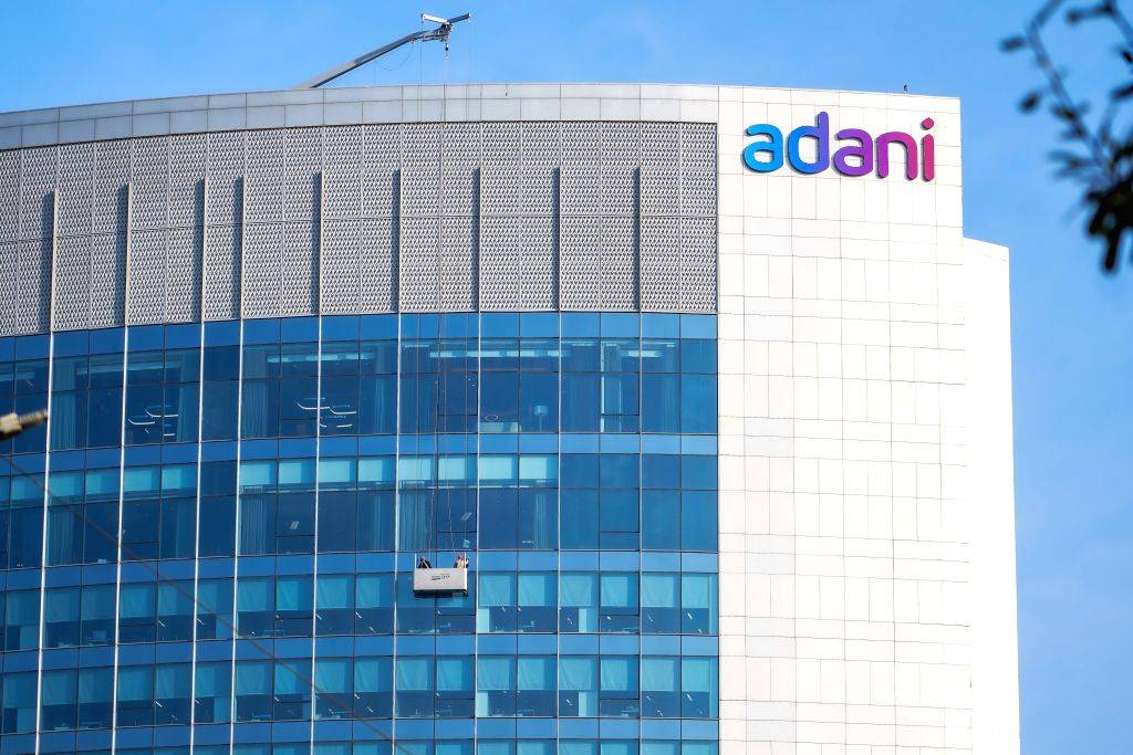 Workers clean the glass facade of Adani House