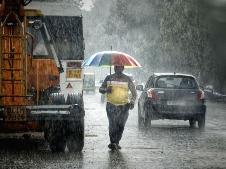 A man holding an umbrella tries to protect from rain