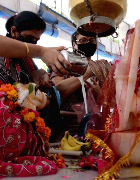 Hindu devotees perform rituals pouring milk and water on a Shiva Lingam ...