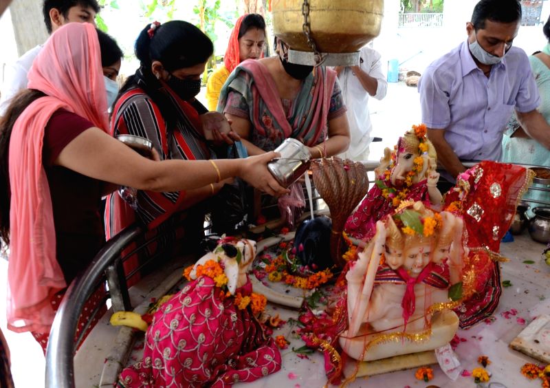 Hindu devotees perform rituals pouring milk and water on a Shiva Lingam ...